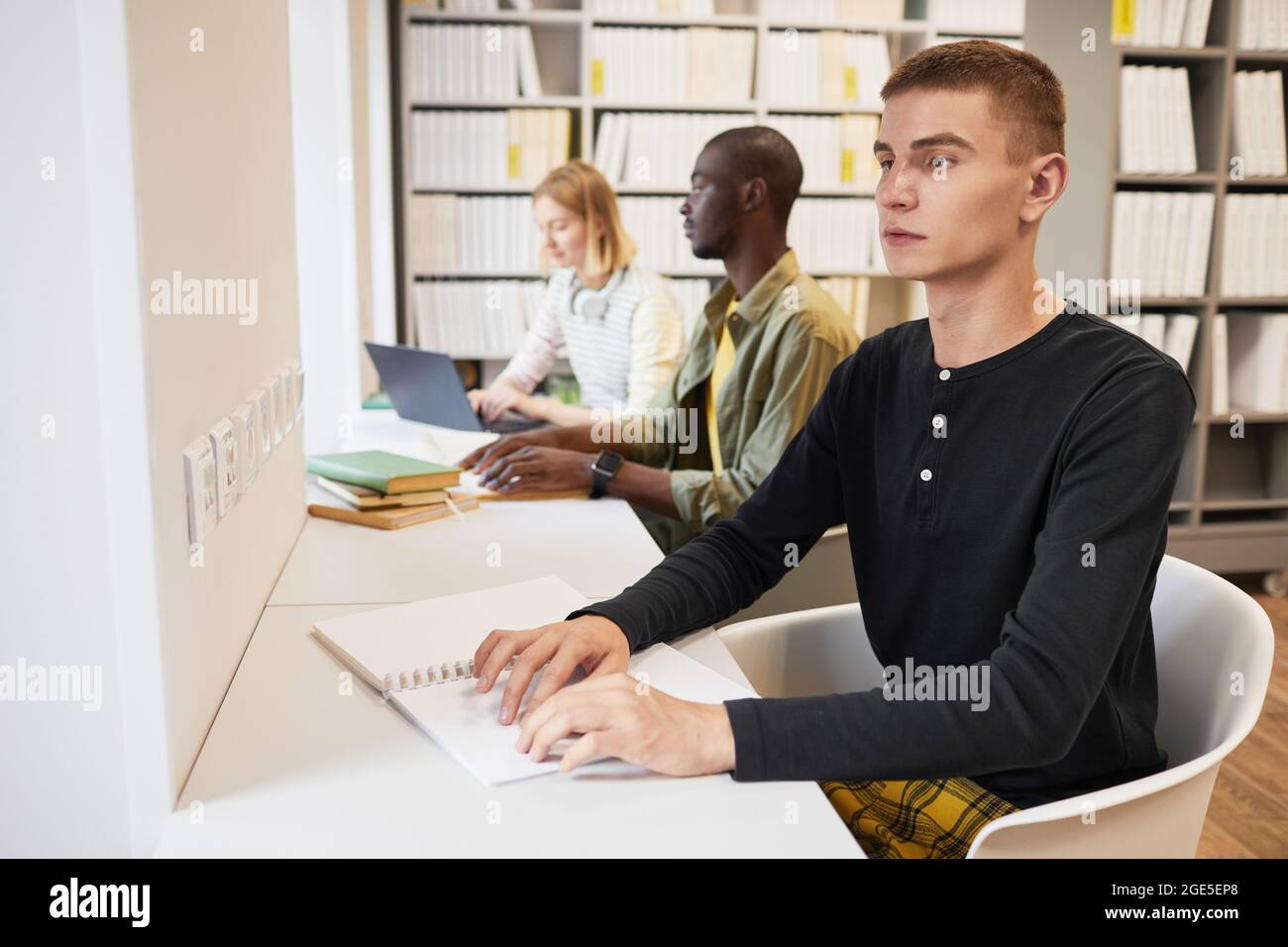 Side view at group of students with young man reading braille book in ...