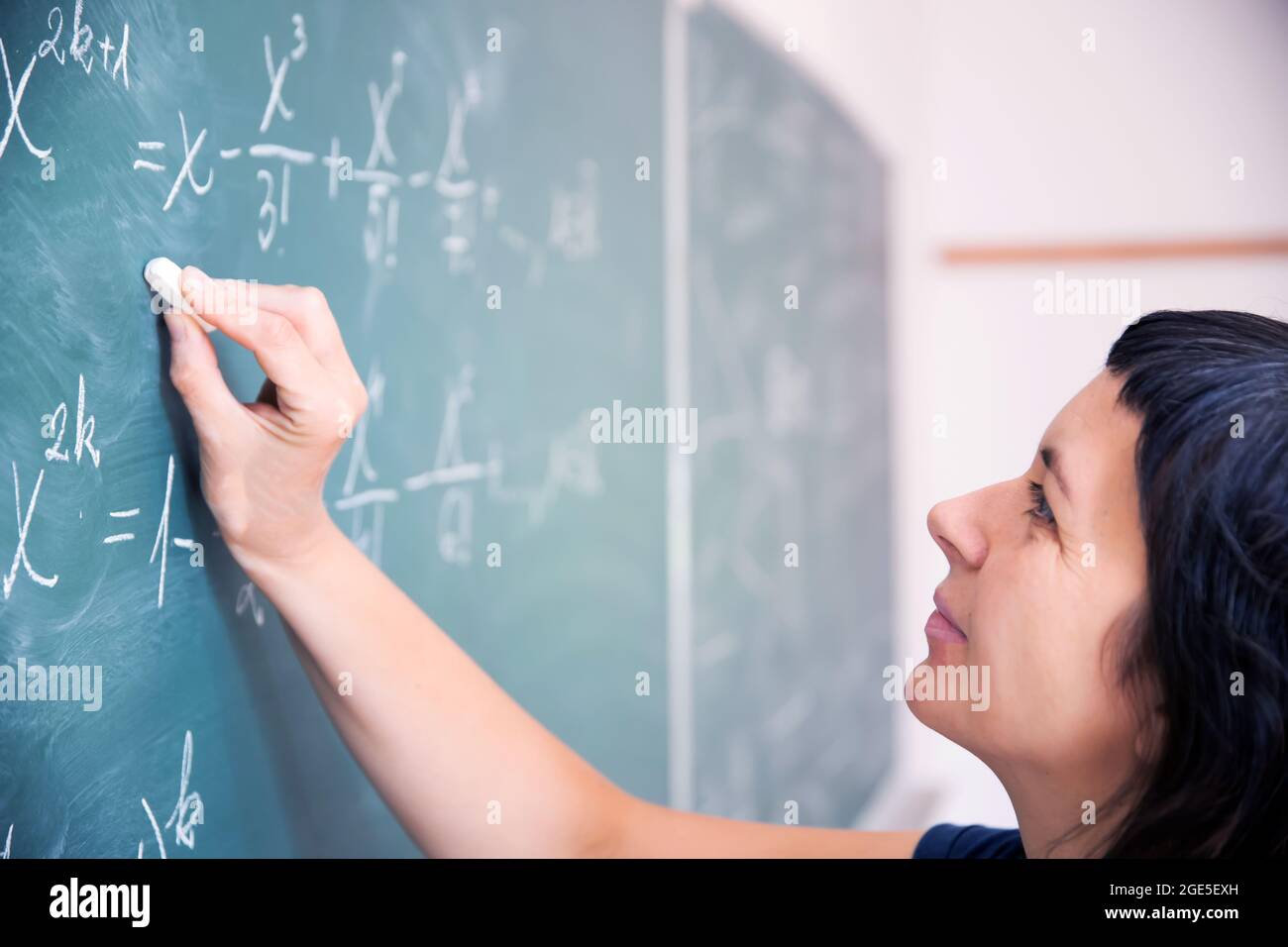 Teacher or student writing on blackboard during math lesson in school ...