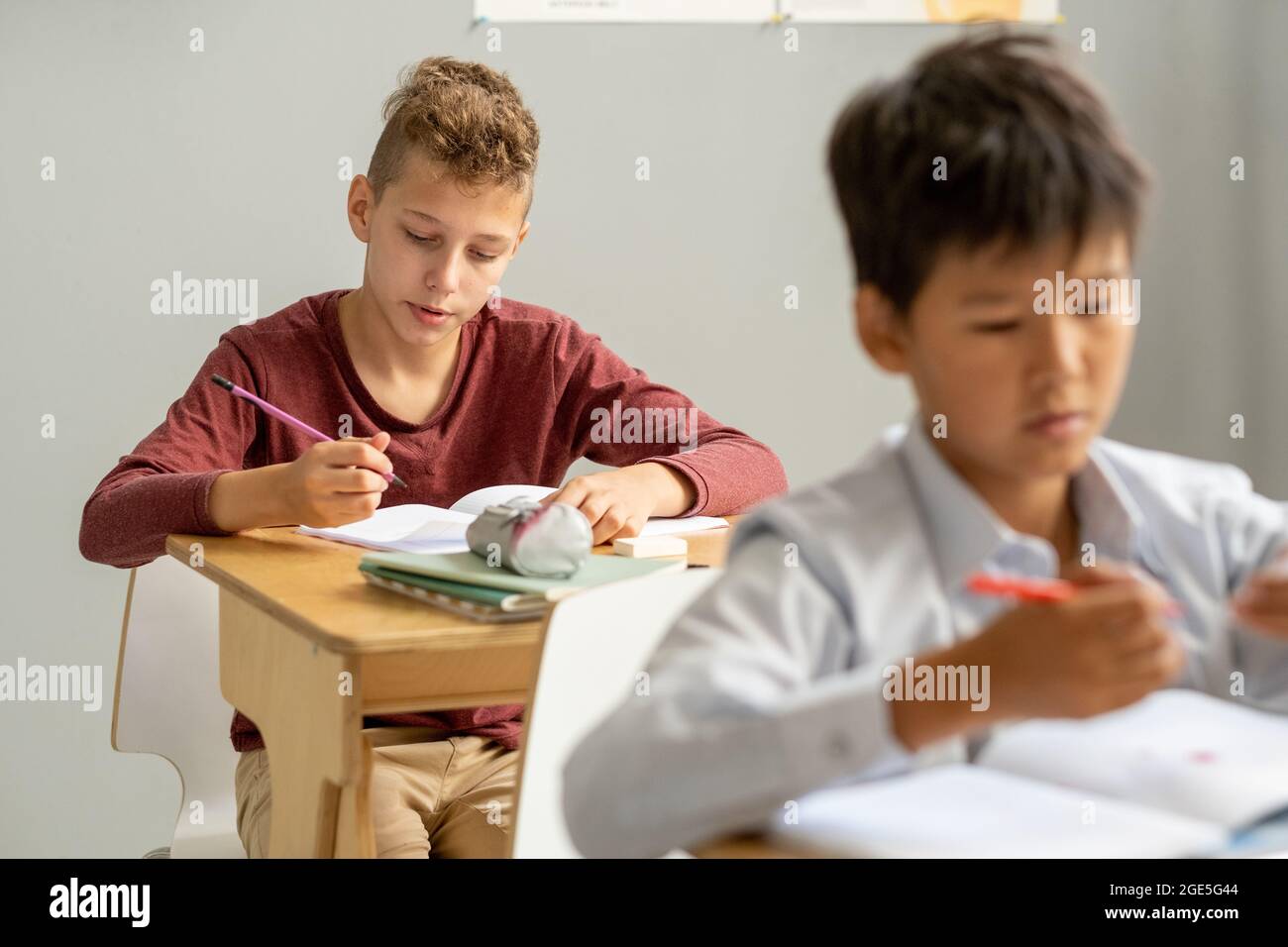 Cute schoolboy looking though his notes in copybook at lesson Stock ...