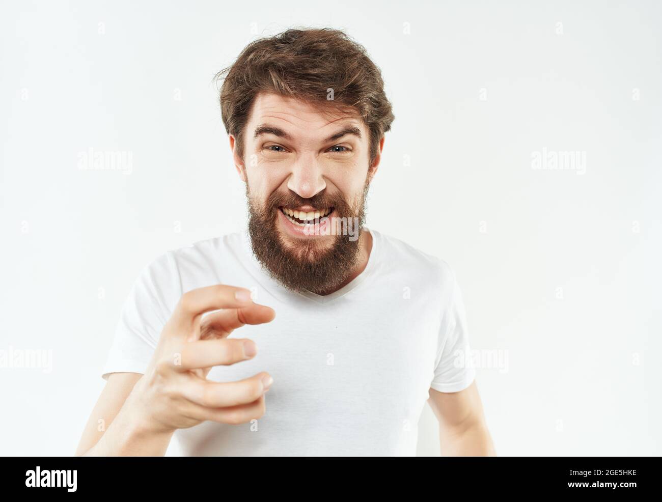 Man in a white t-shirt irritated facial expression light background ...