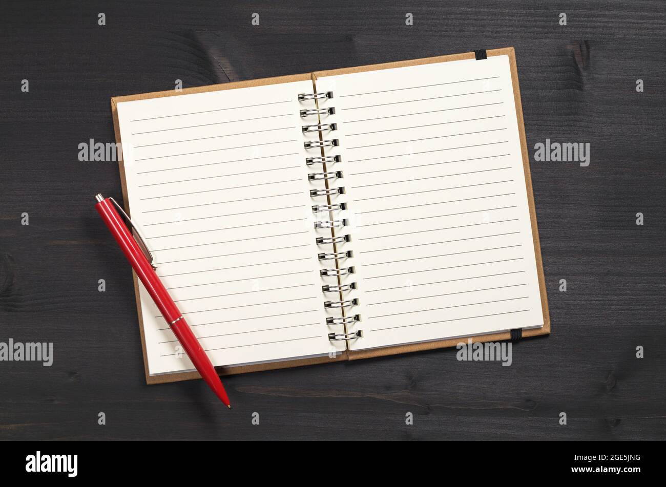 Notepad in hardcover with a red pen on black wooden background, top ...