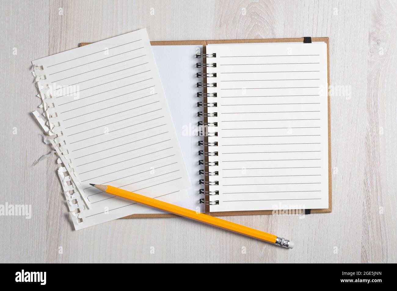 Notepad, empty sheets and pencil on light wooden desk, top view. Space ...