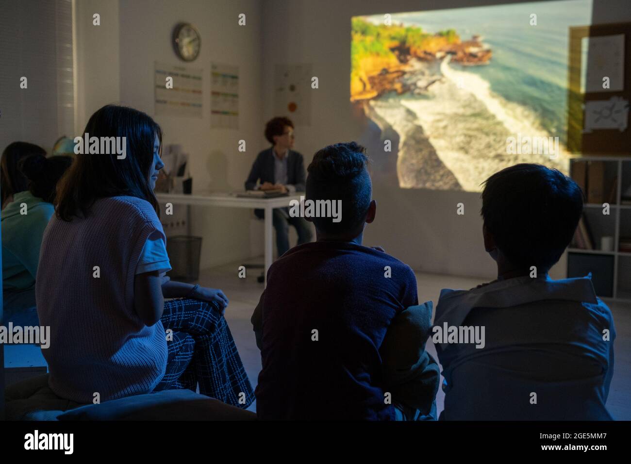 Group of schoolkids watching video about natural environment in dark ...