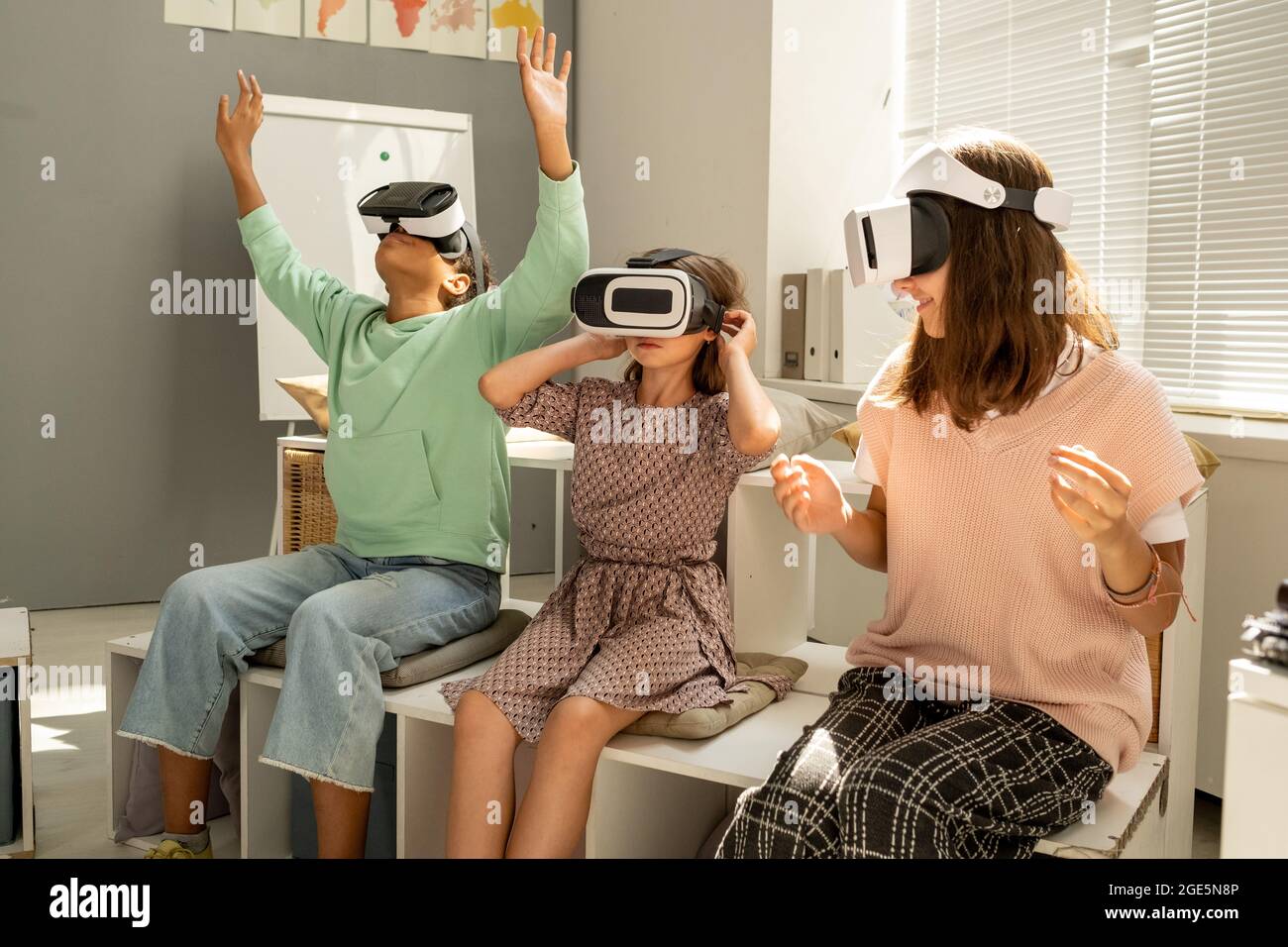 Three intercultural schoolgirls in vr headsets watching virtual ...