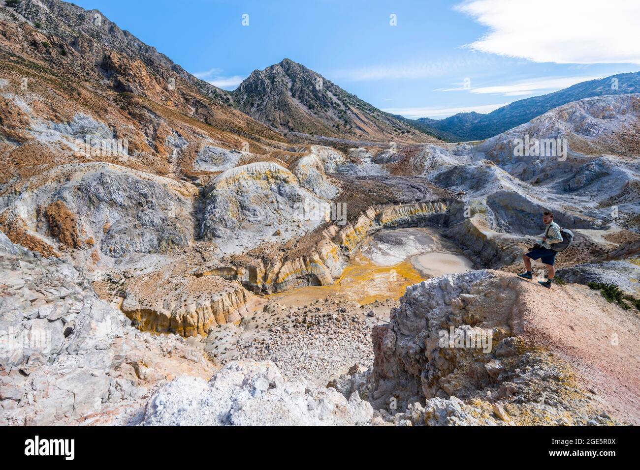 Young man at the crater rim, crater with yellow discoloured sulphur ...