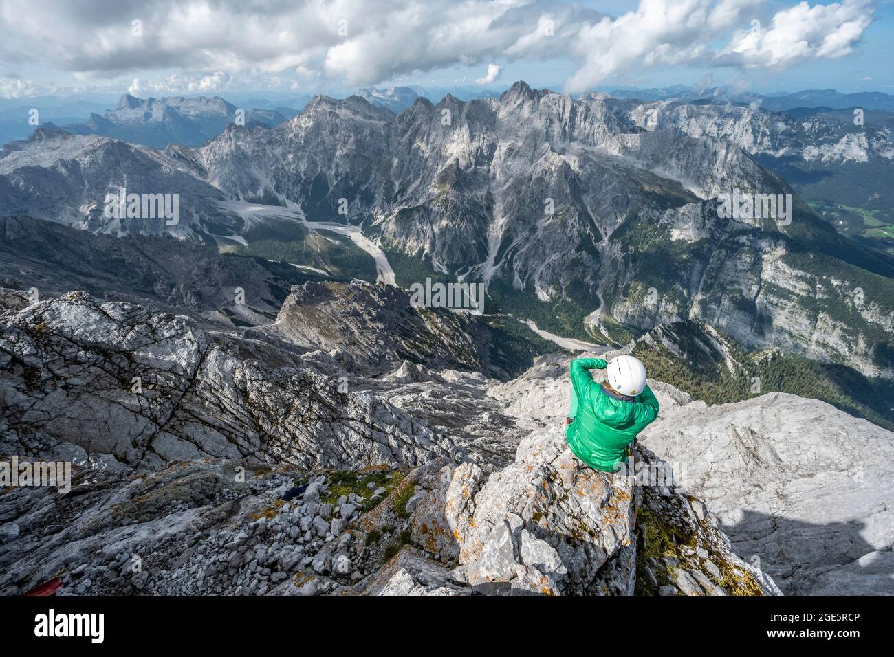 Hiker with helmet at the summit of the Watzmann, view over mountains ...
