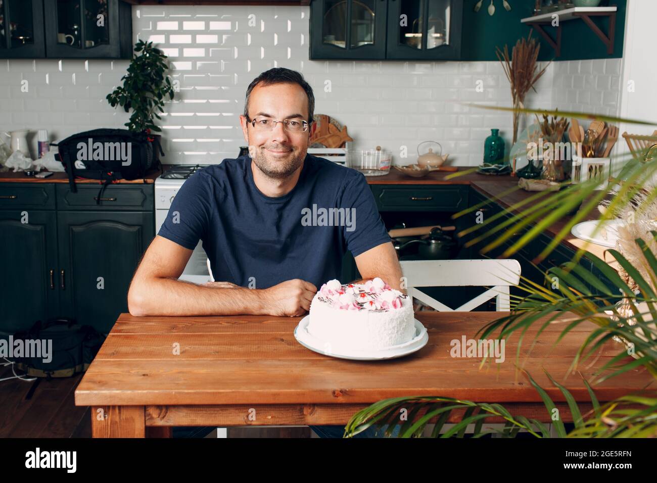 Man sit in home kitchen with cake on table Stock Photo - Alamy