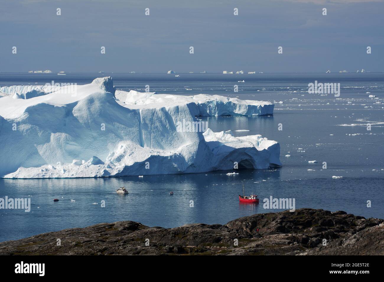 View of small fishing boat and bay with icebergs, ice fjord, sermermuit ...
