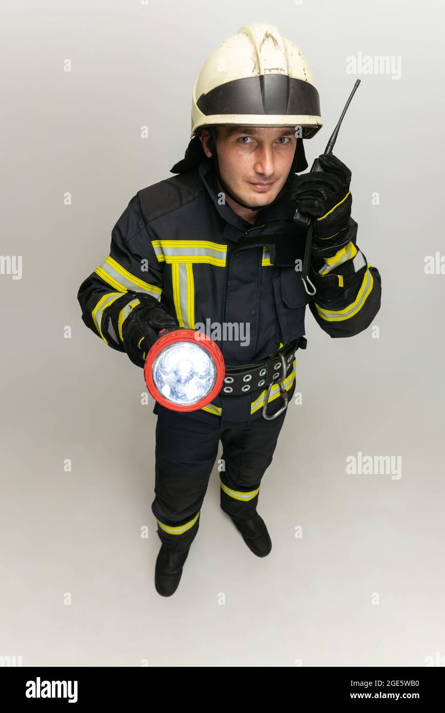 One male firefighter dressed in uniform posing over white studio ...