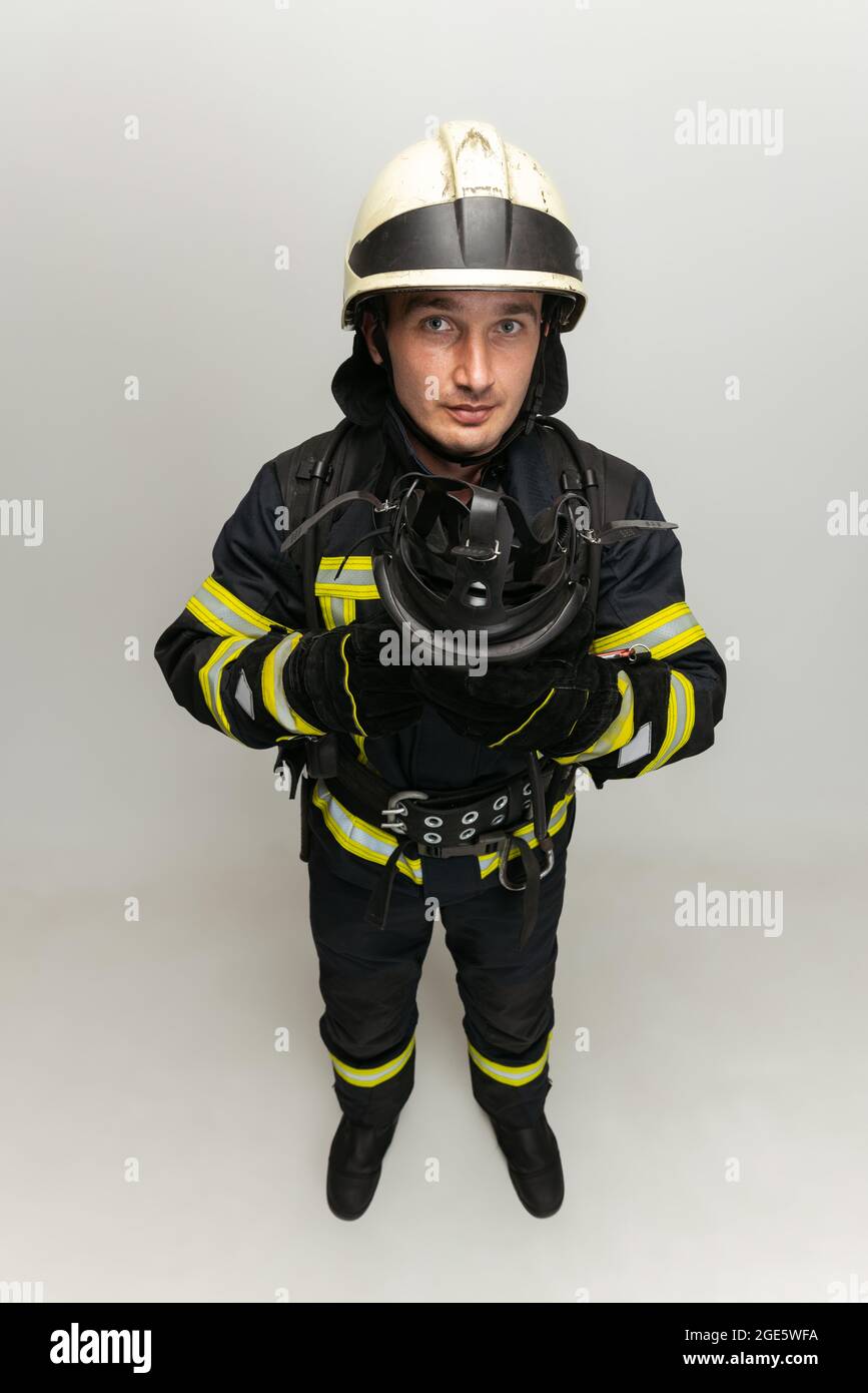 One male firefighter dressed in uniform posing over white studio ...