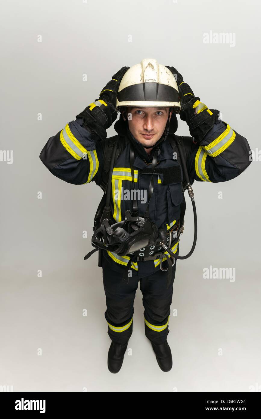 One male firefighter dressed in uniform posing over white studio ...