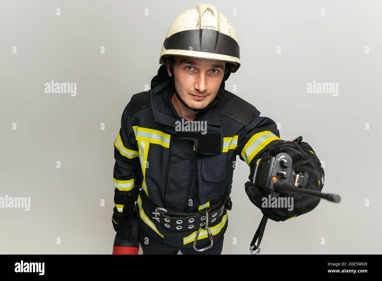 One male firefighter dressed in uniform posing over white studio ...