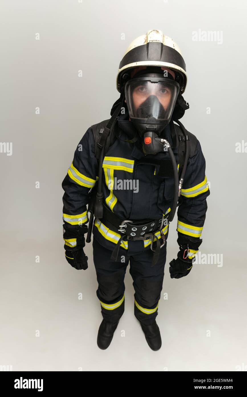 One male firefighter dressed in uniform posing over white studio ...