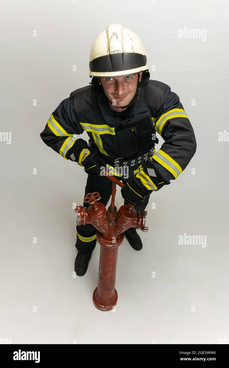 One male firefighter dressed in uniform standing at fire hydrant over ...