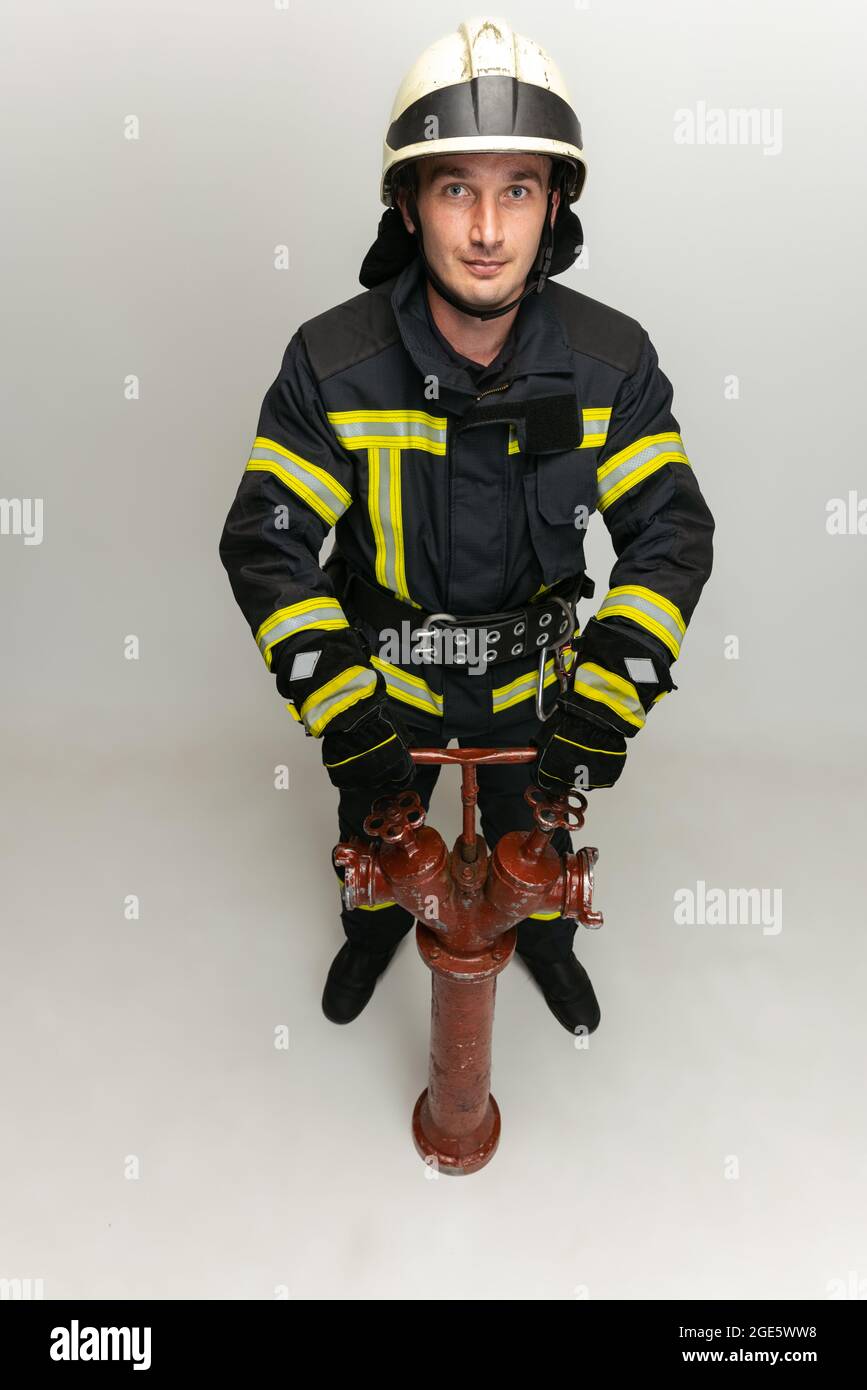 One male firefighter dressed in uniform standing at fire hydrant over ...