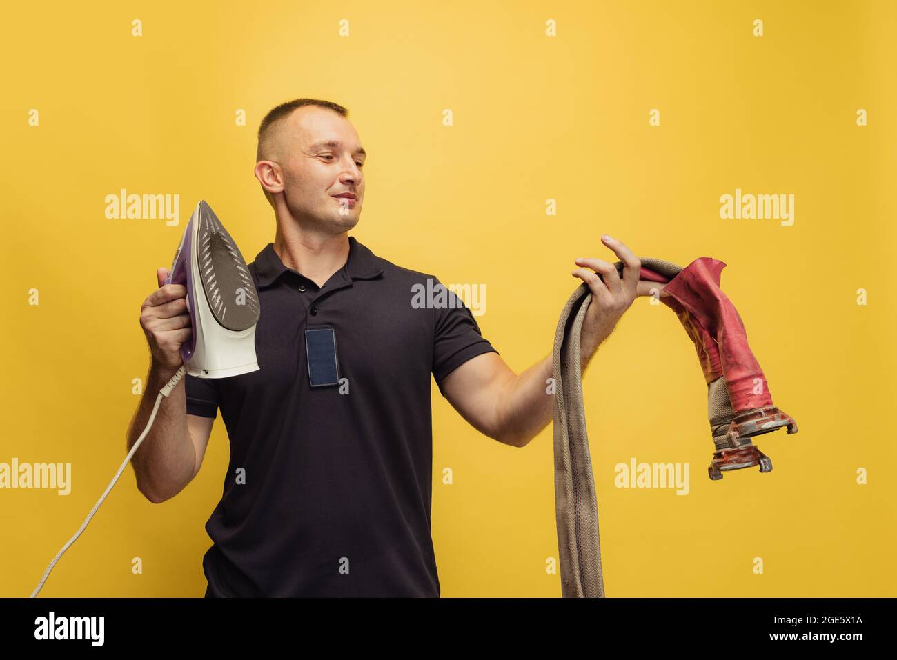 One brutal smiling man posing with iron and fire hose over yellow ...