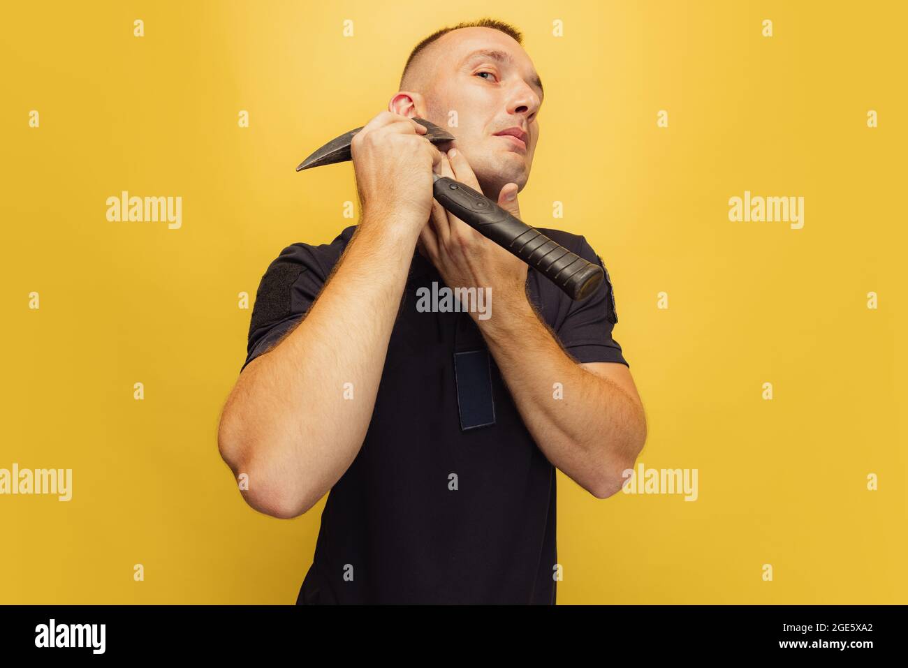 One young brutal man, firefighter shaving with an axe over yellow ...