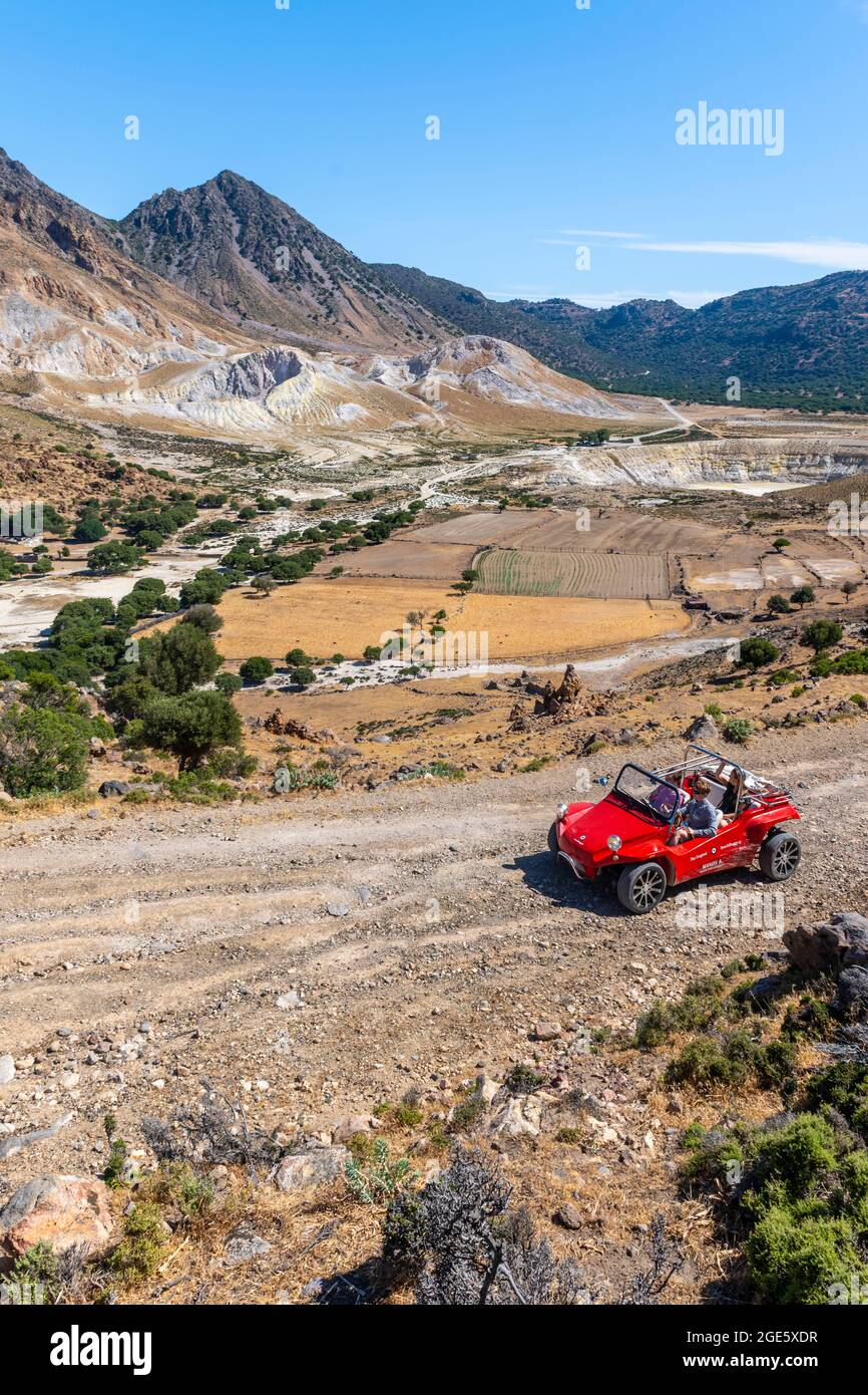 Tourists explore Nysiros with a red car on a gravel road, volcano ...