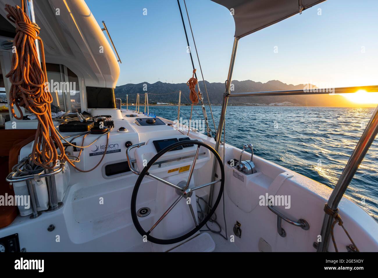 Steering wheel in the cockpit on deck of a sailing catamaran, ropes ...