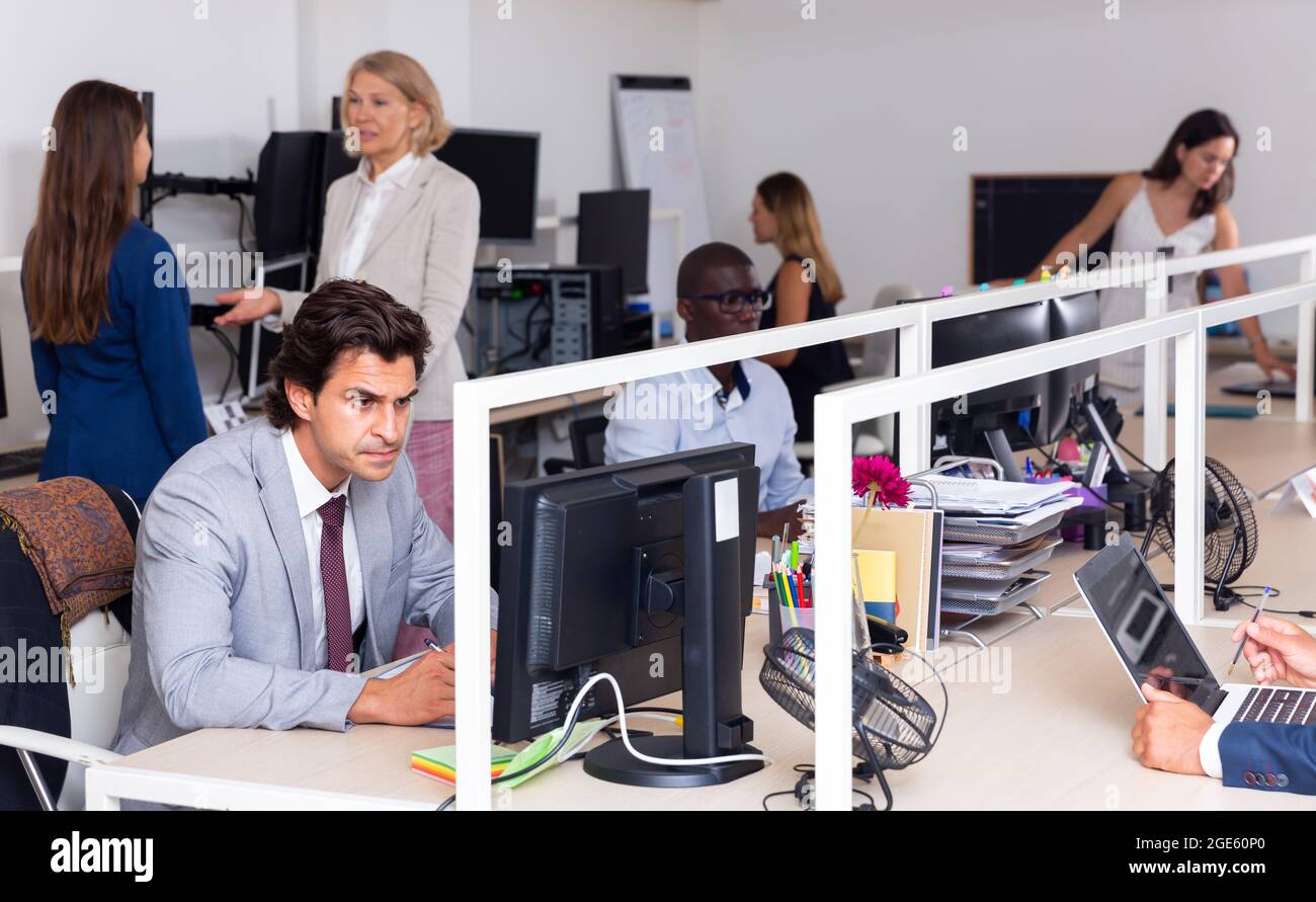Confused male worker among working colleagues Stock Photo - Alamy