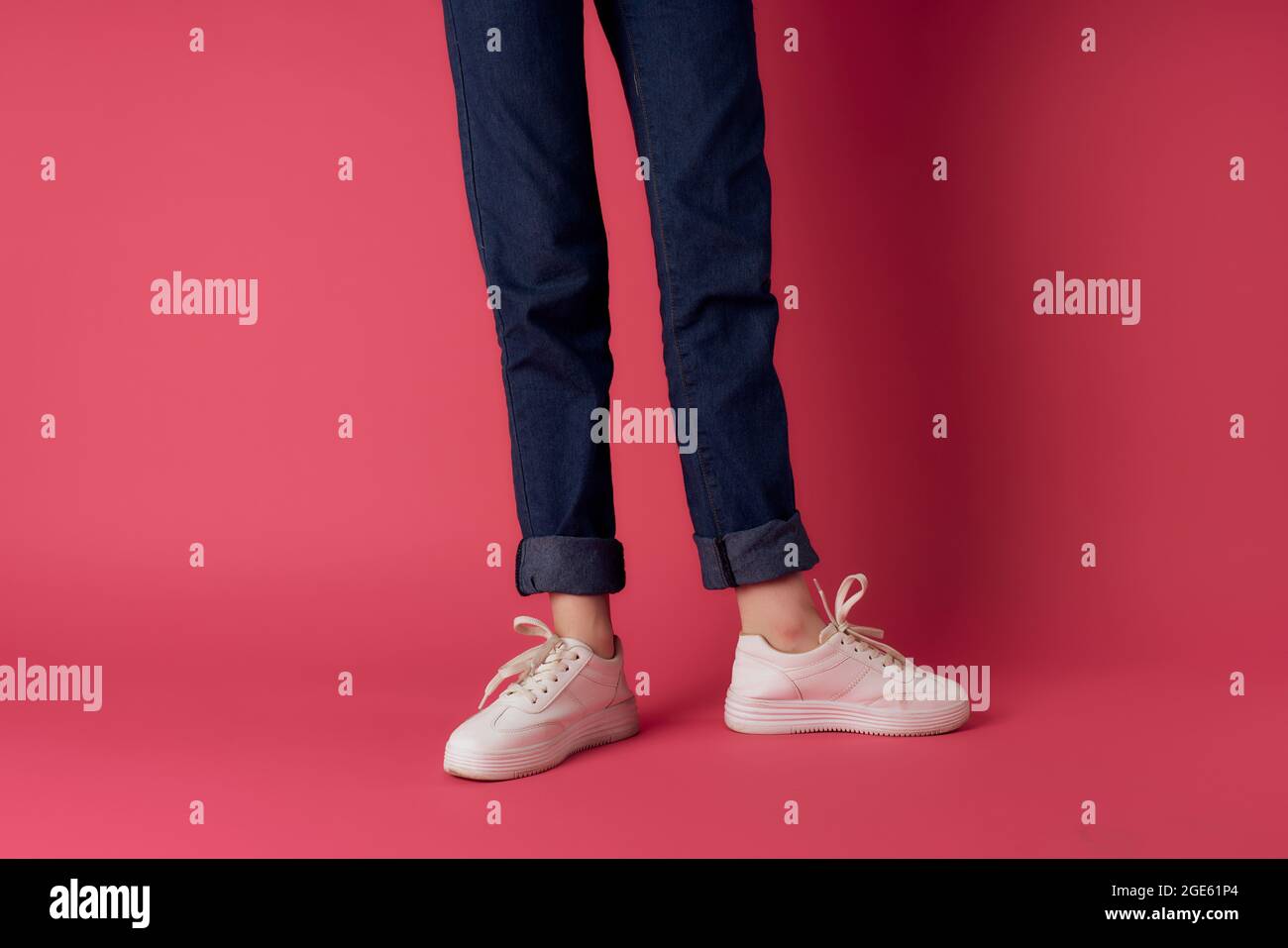 female legs in white sneakers upside-down view pink background fashion ...