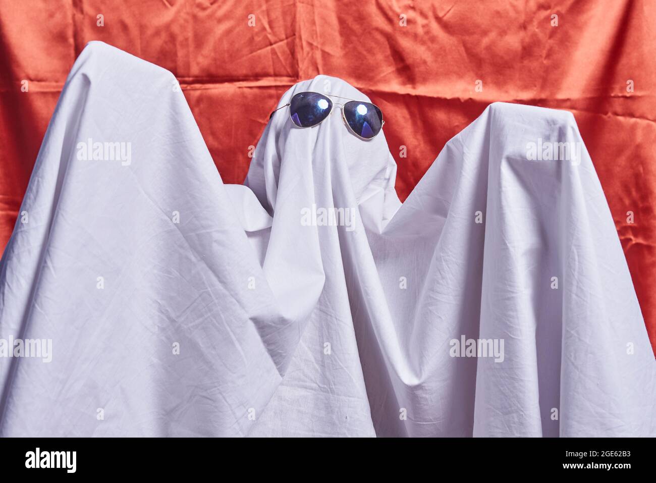White ghost on orange. Halloween holiday. A young child dressed in a ...