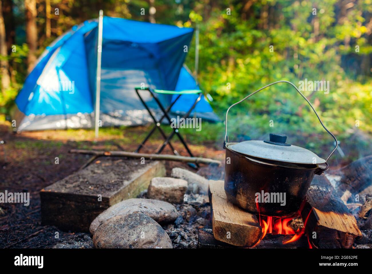 Camping in summer forest. Cooking on campfire in cauldron pot by hiking ...