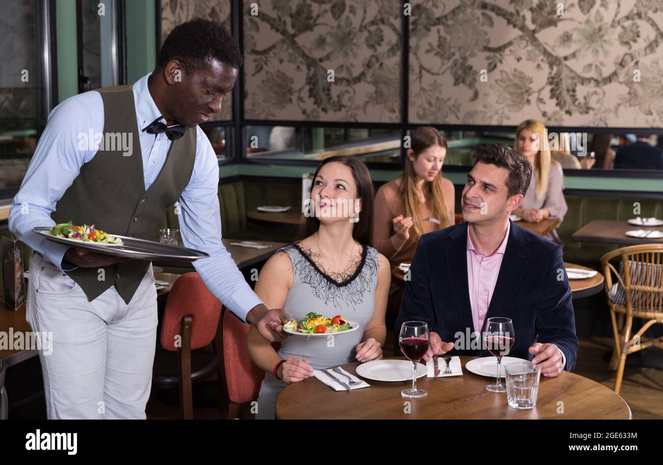African American waiter serving couple at restaurant Stock Photo - Alamy