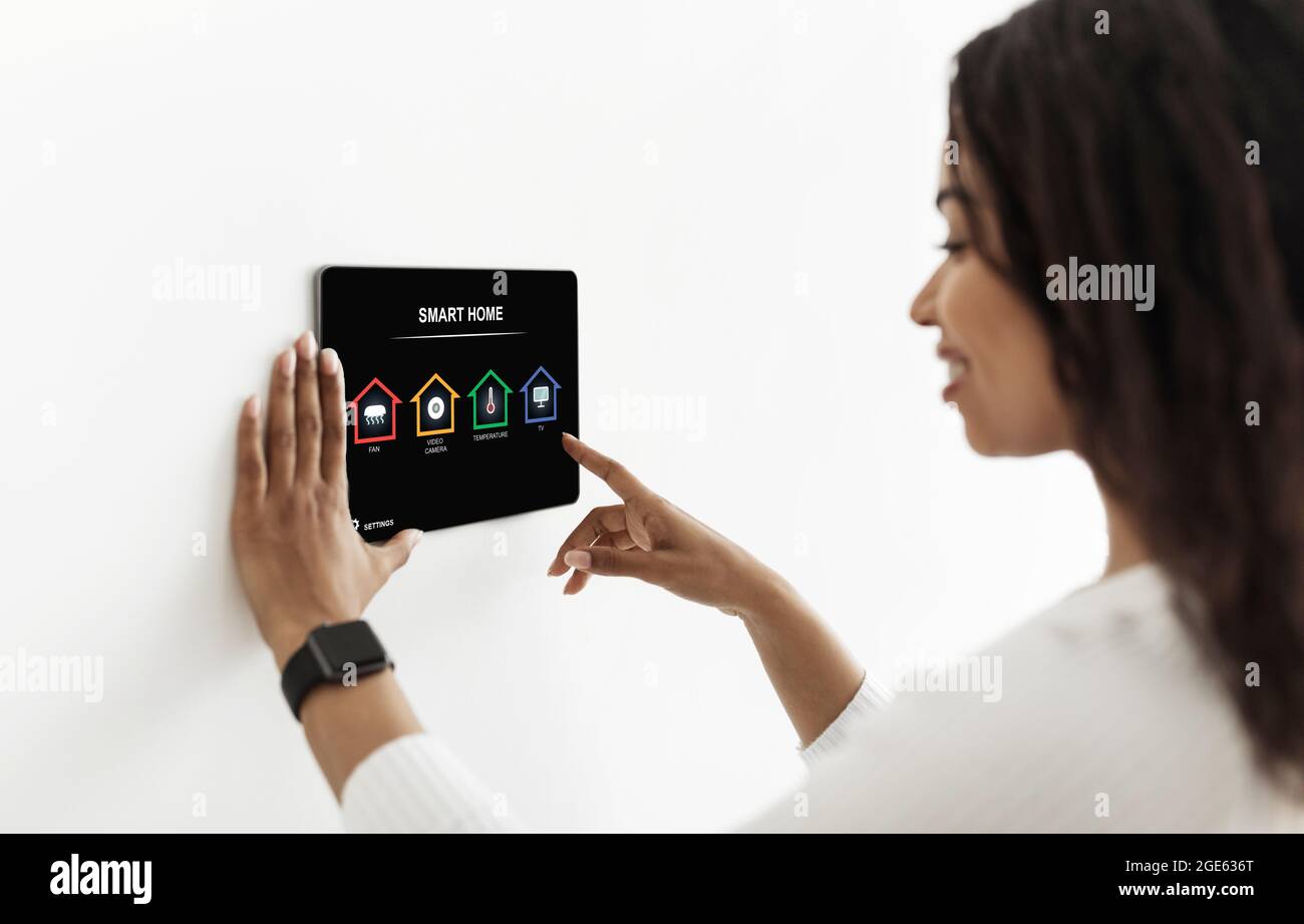 Modern smart home electronic systems concept. Black lady using smart ...