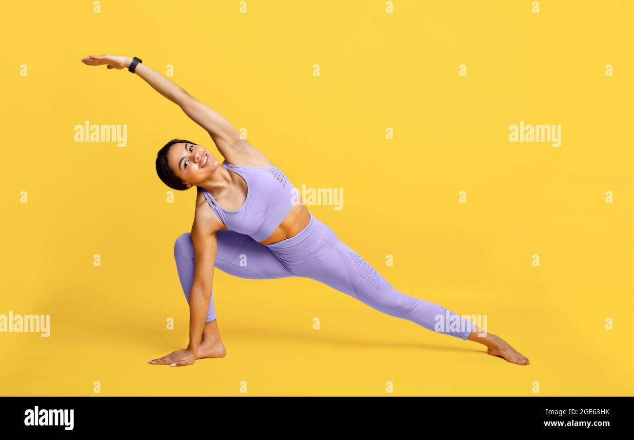 Wellness concept. Fit black woman standing in yoga pose on yellow ...