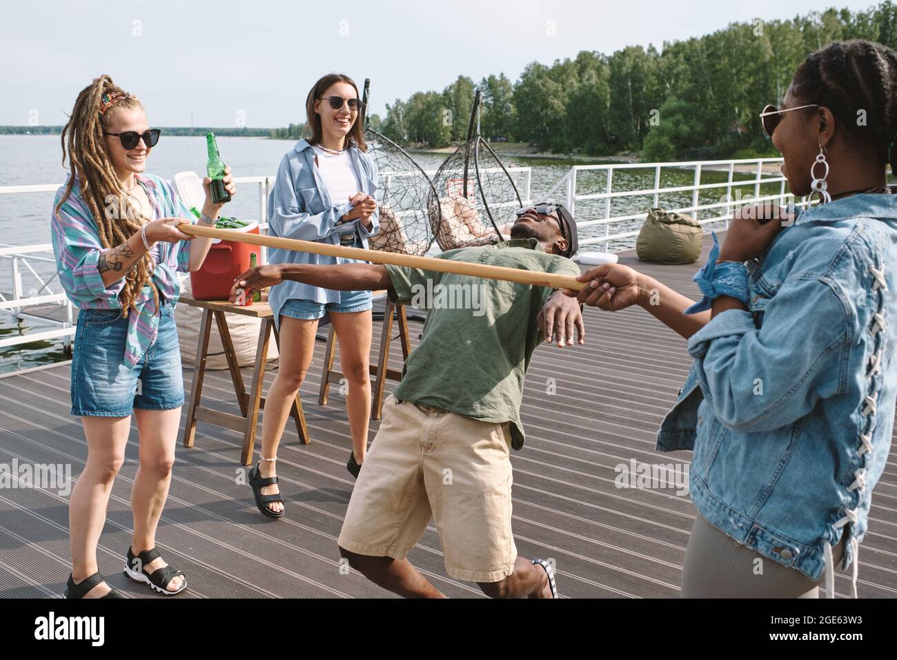 Young man bending backwards to walk under vertical bar in hands of his ...