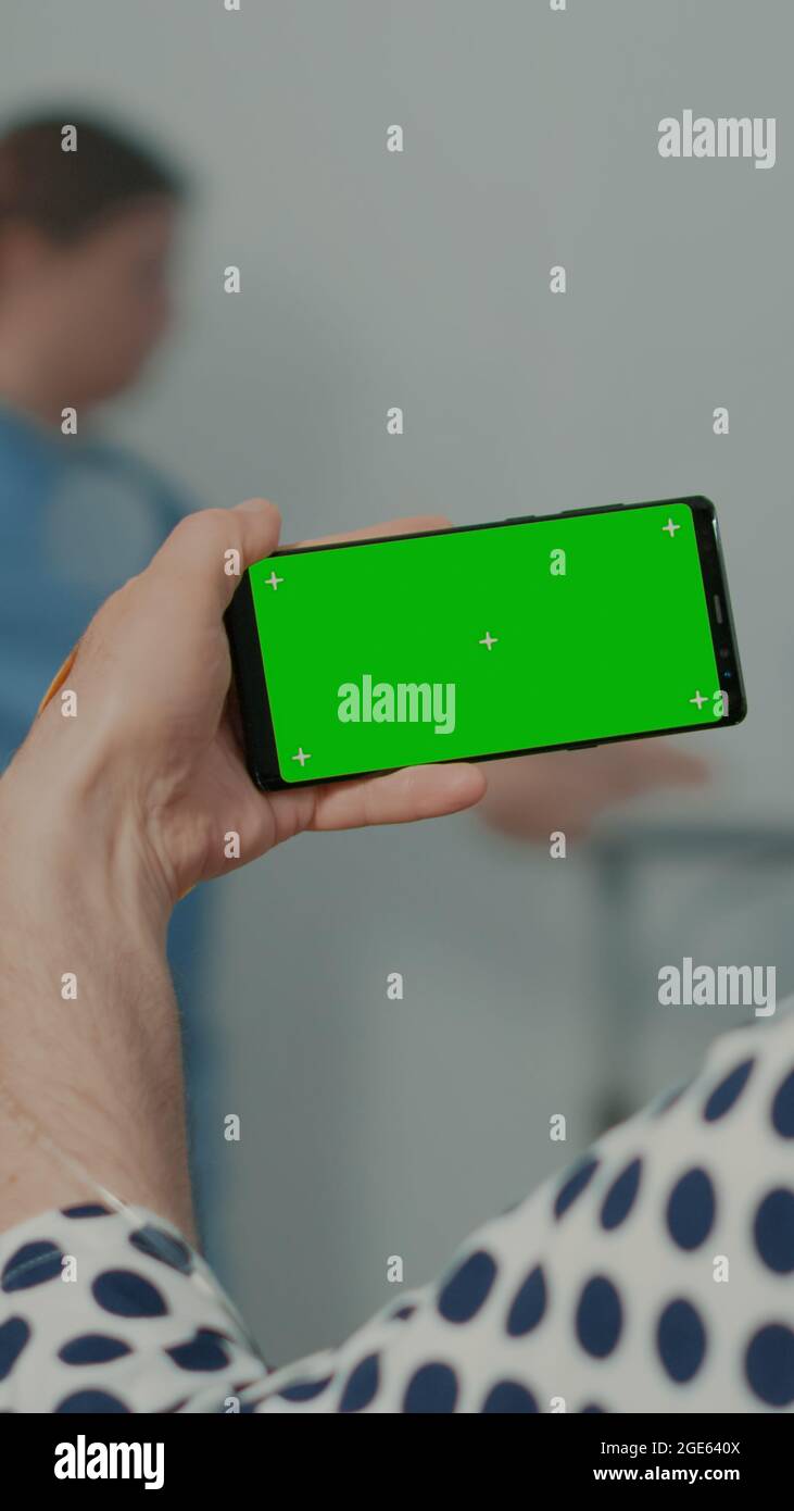 Sick old man holding green screen device at facility in hospital ward ...