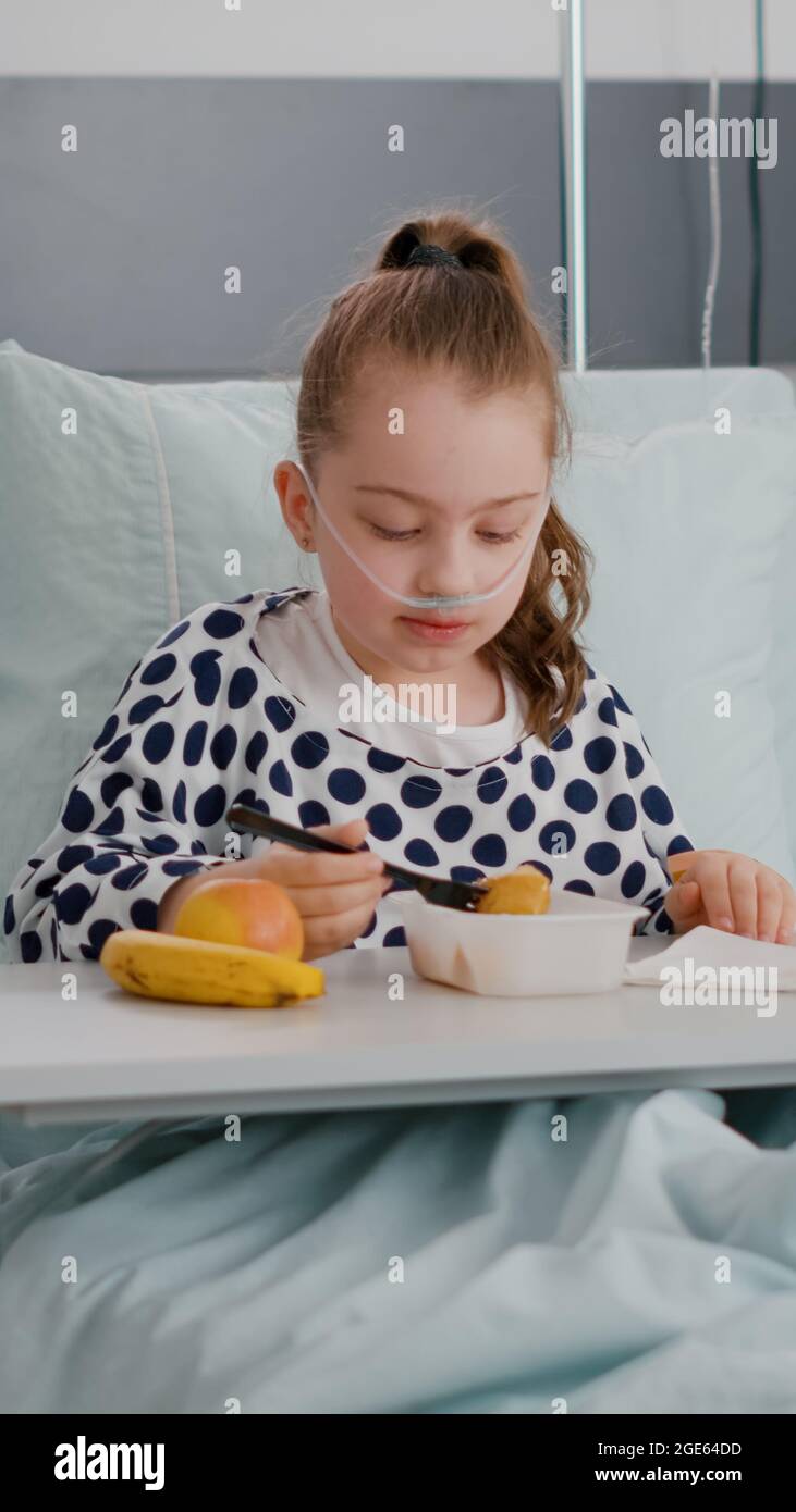 Portrait of hospitalized little child resting in bed eating healthy ...
