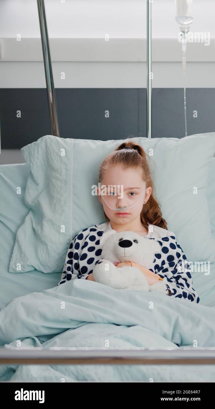 Portrait of hospitalized sick girl child patient holding teddy bear ...