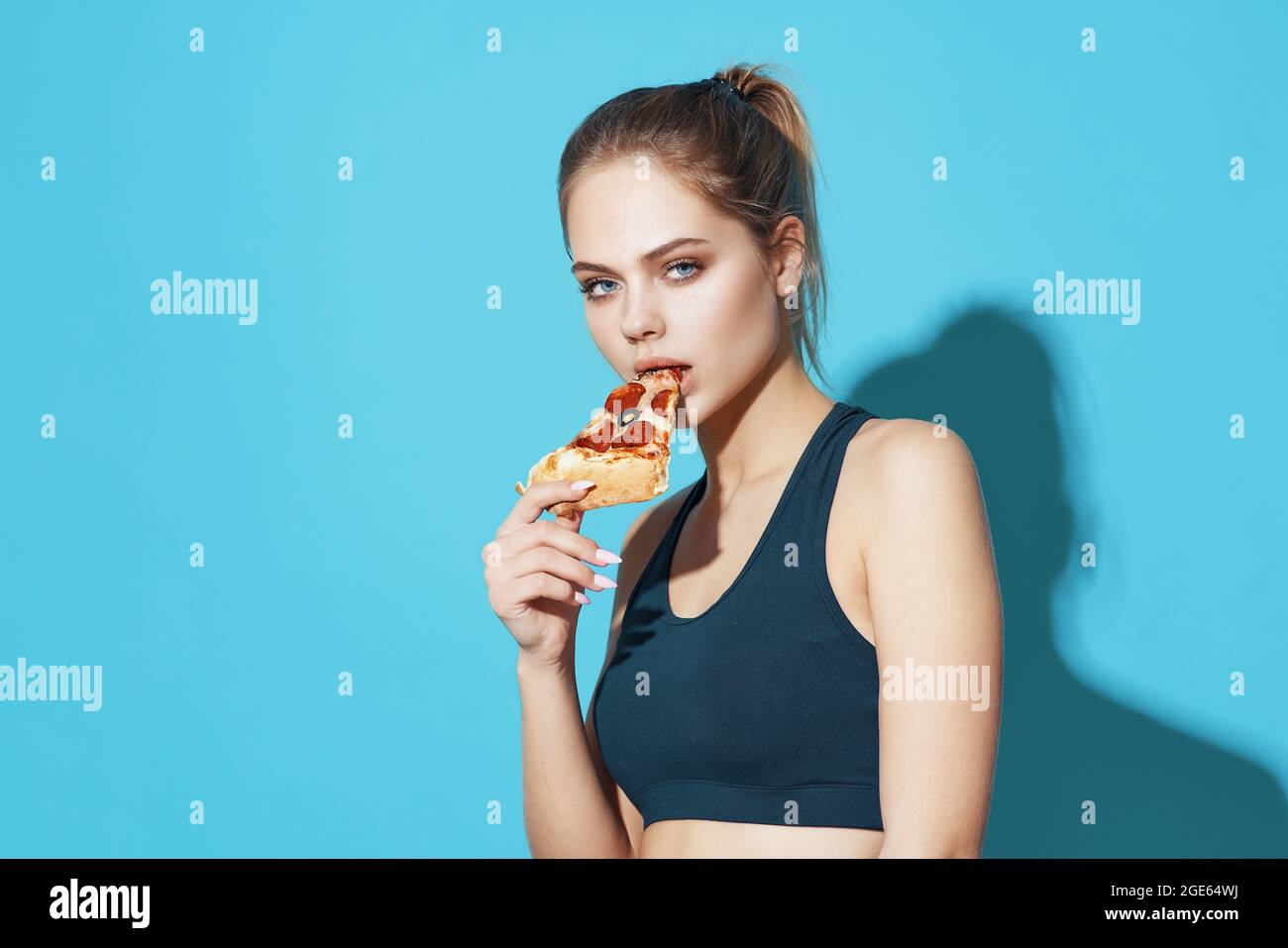 woman in sports uniform eating pizza food diet blue background Stock ...