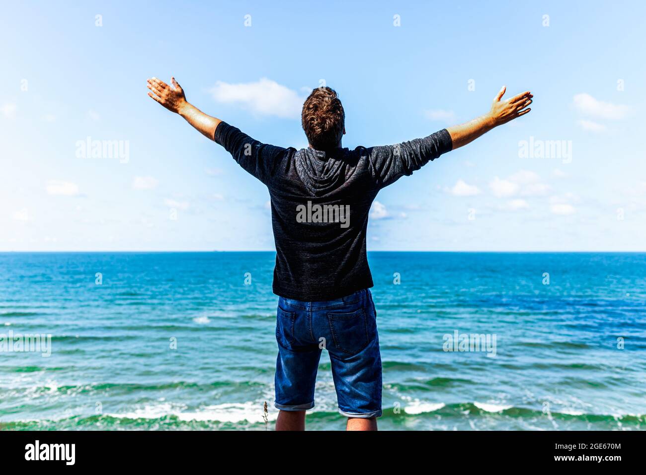 Caucasian man spreading arms and watching the ocean. happy man with ...