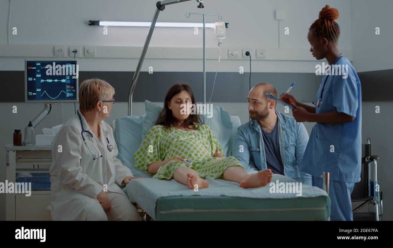 Multi ethnic doctor and nurse talking to pregnant woman sitting in ...