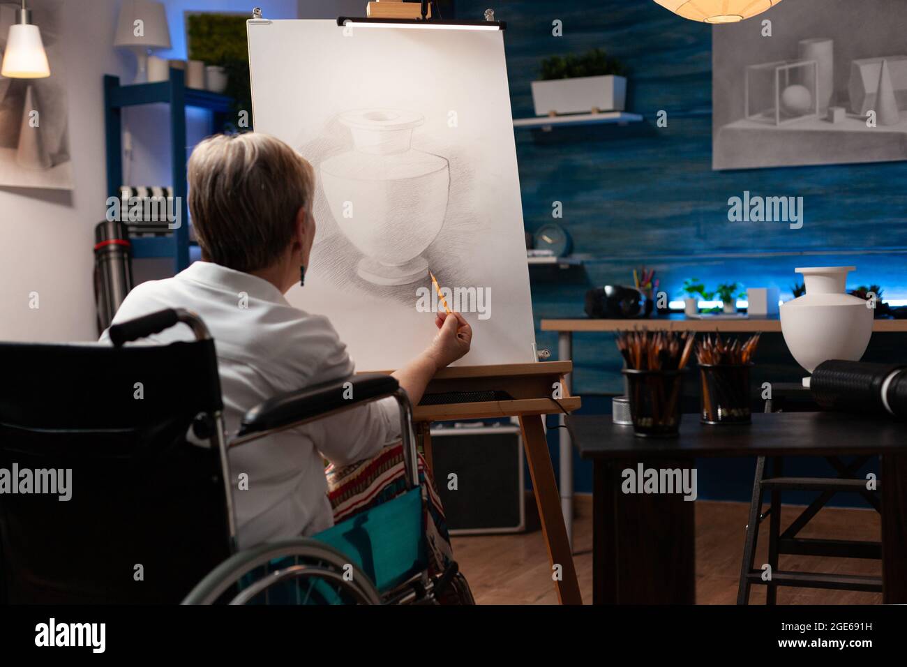 Disabled elder artist drawing vase design on canvas in artwork studio ...