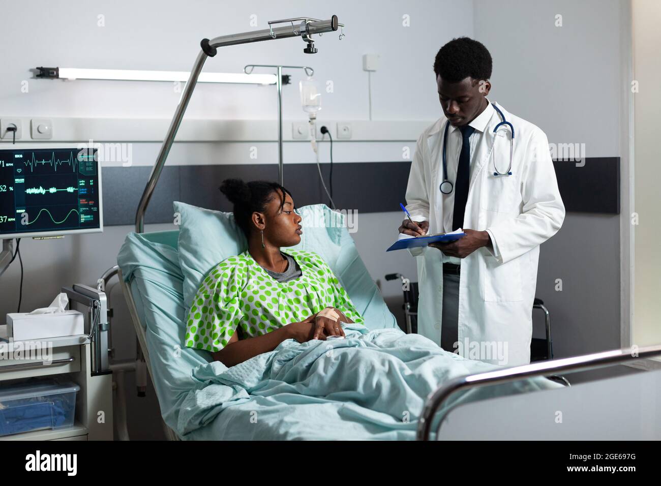 Disease doctor sitting with young afro patient in hospital ward talking ...