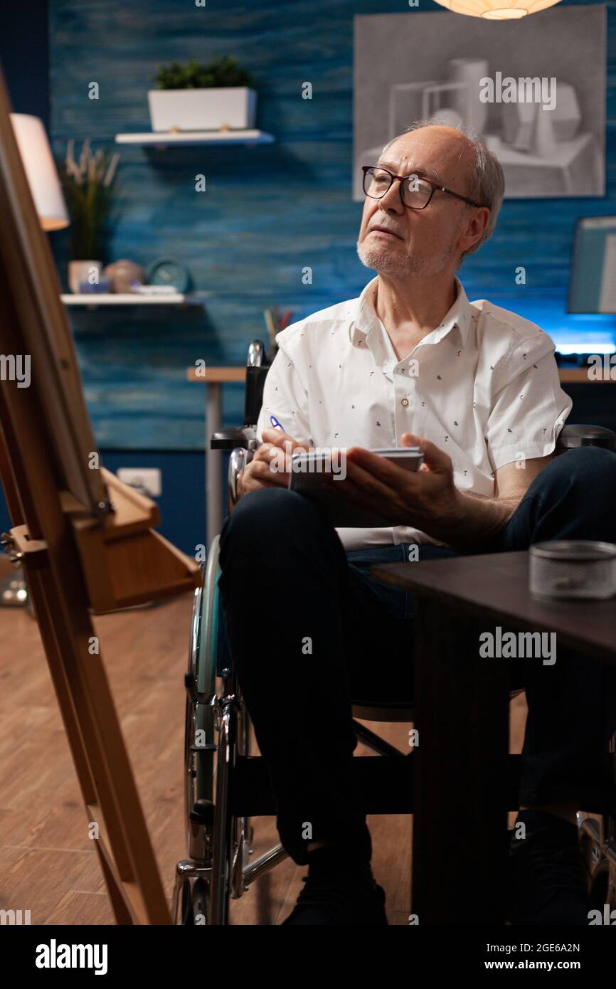 Disabled elder man working on sketch with notebook for masterpiece ...