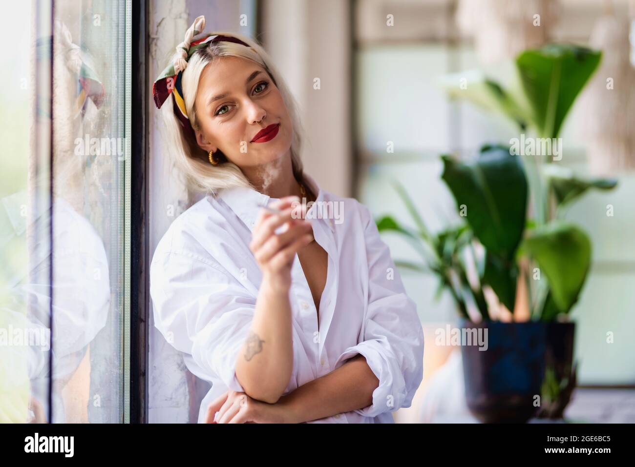 Portrait shot of beautiful young woman wearing hair scarf and white ...