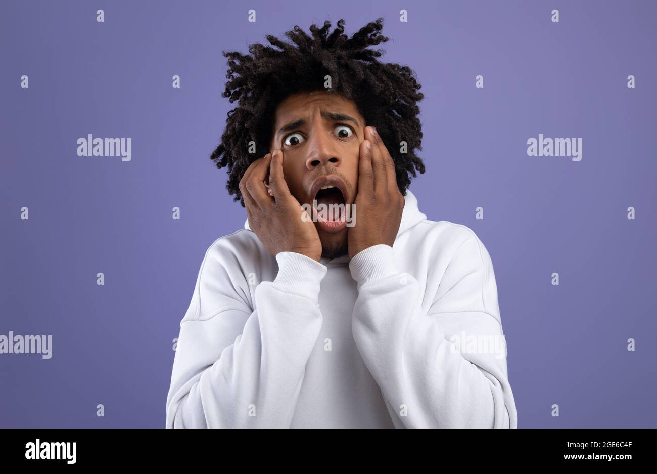 Black teen guy feeling scared, shouting in panic on violet studio ...