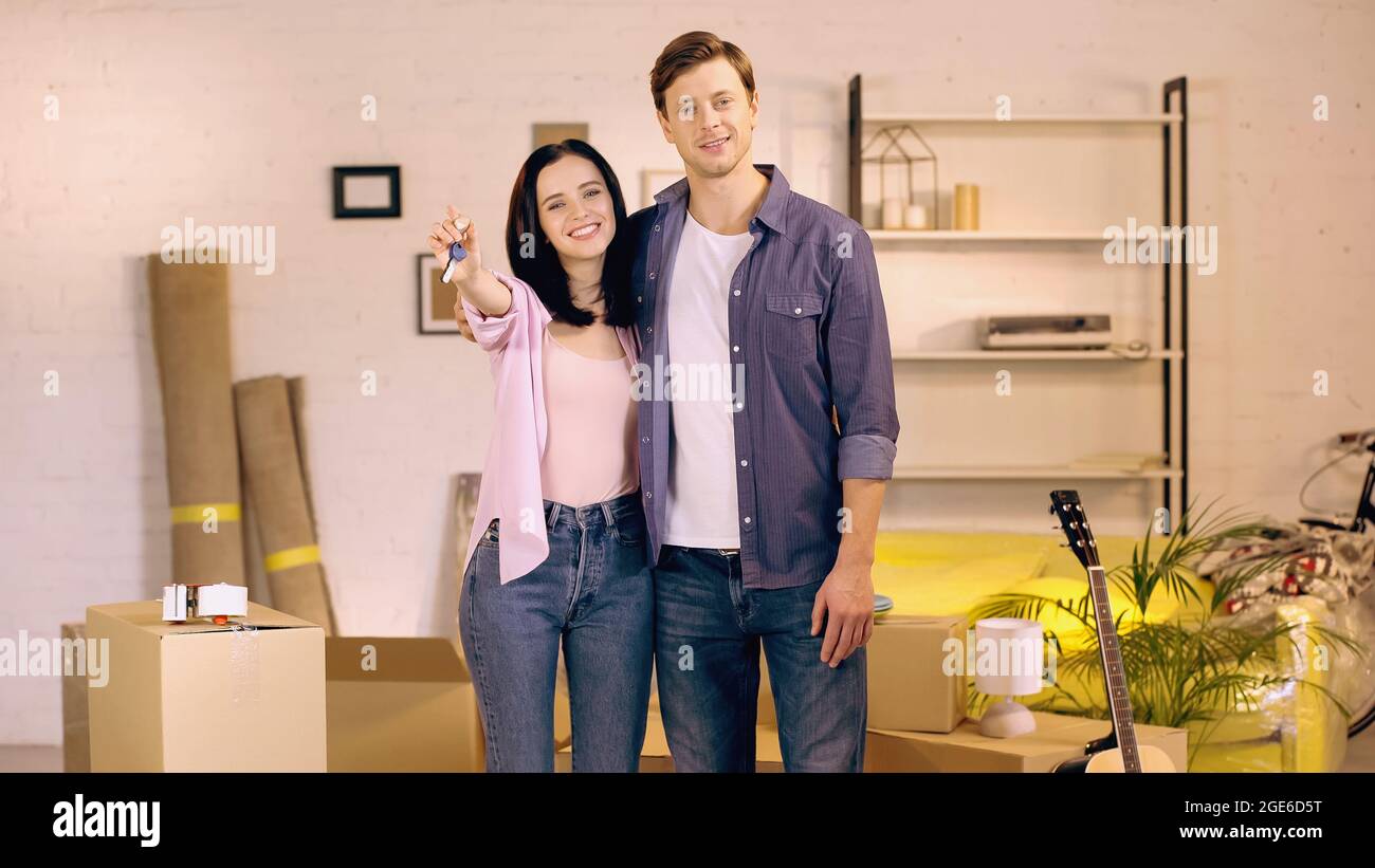 Smiling couple showing keys near boxes in new home,stock image Stock ...