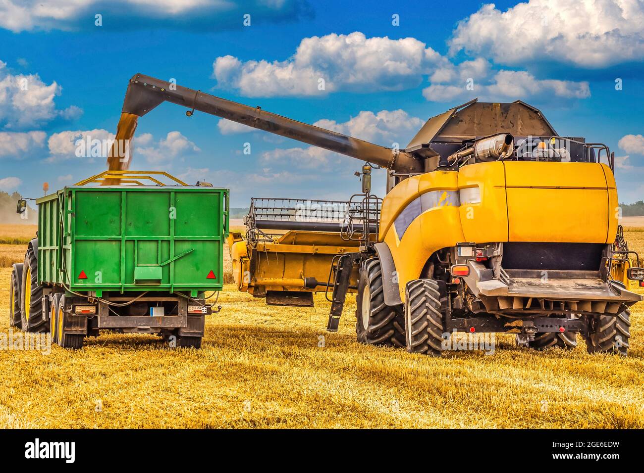 Combine Harvester Unloading Grain into the Tractor on The Agricultural ...