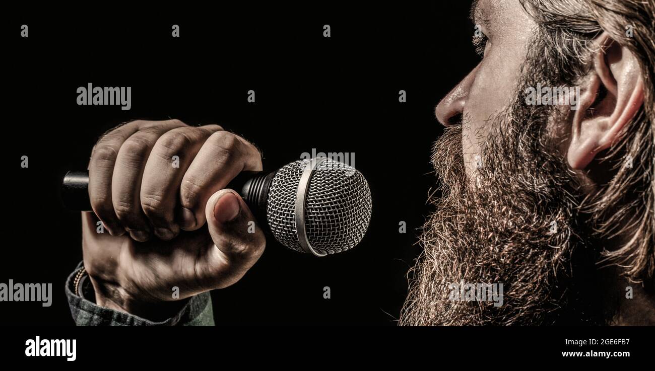 Bearded man in karaoke sings a song into a microphone. Male attends ...