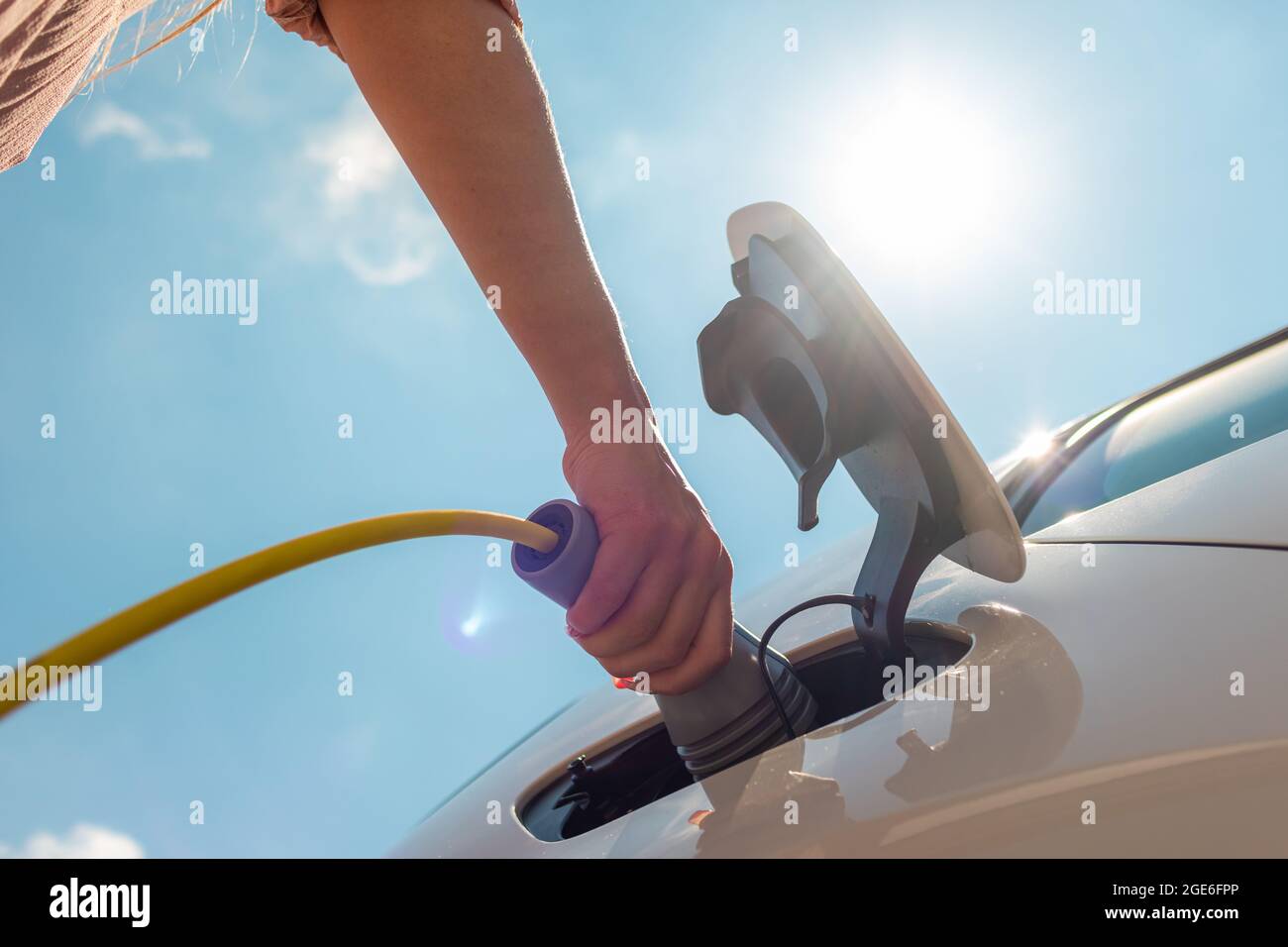 Female hands opening an electric car charging socket cap and plugging ...