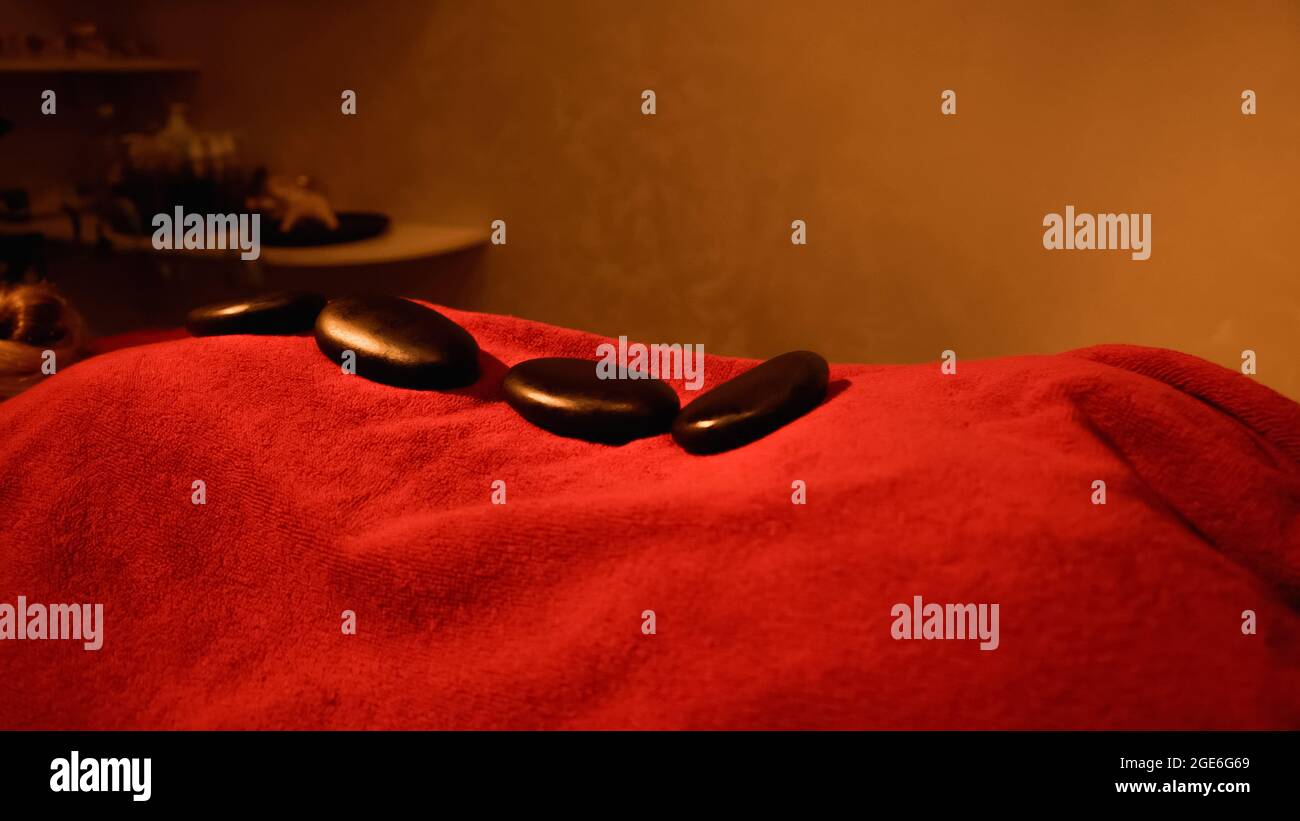 hot stones on back of client lying on massage table Stock Photo - Alamy