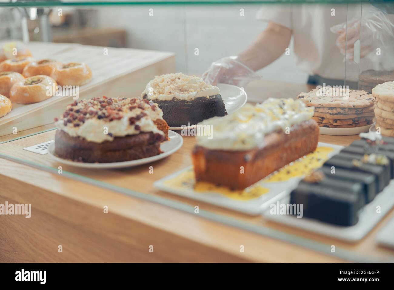 Young woman placing cakes on display showcase Stock Photo - Alamy