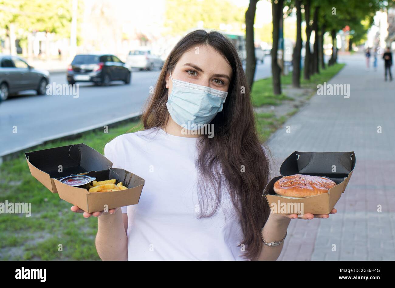 A masked woman deliverer of food during a pandemic and quarantine keeps ...