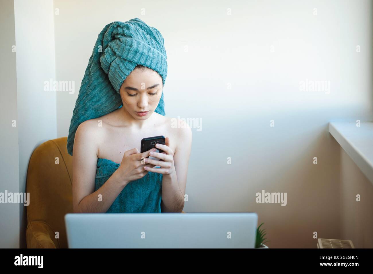 Woman using phone and laptop after bath at home. Beauty and skin care ...